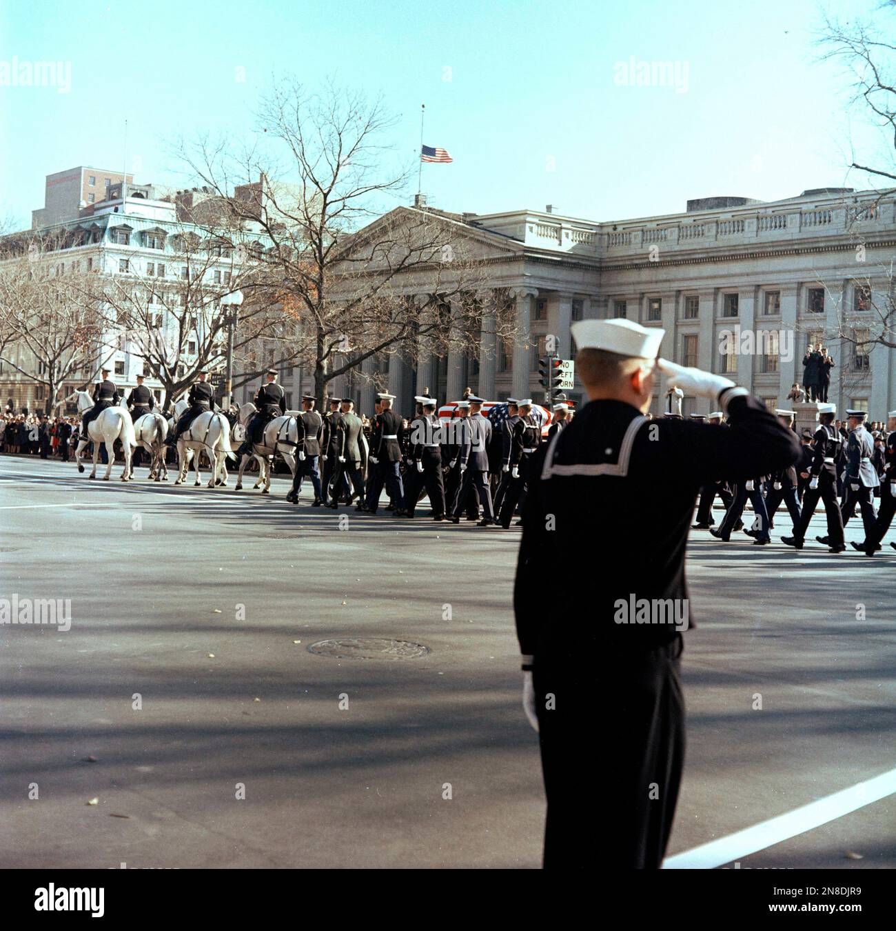 A sailor salutes in the foreground as the funeral procession for ...