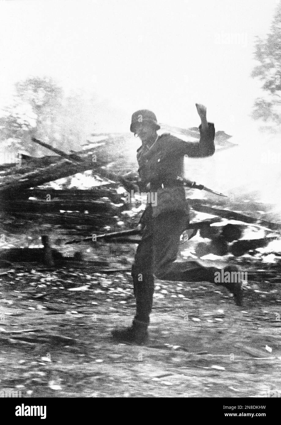A German infantryman runs while a town burns behind him somewhere on ...
