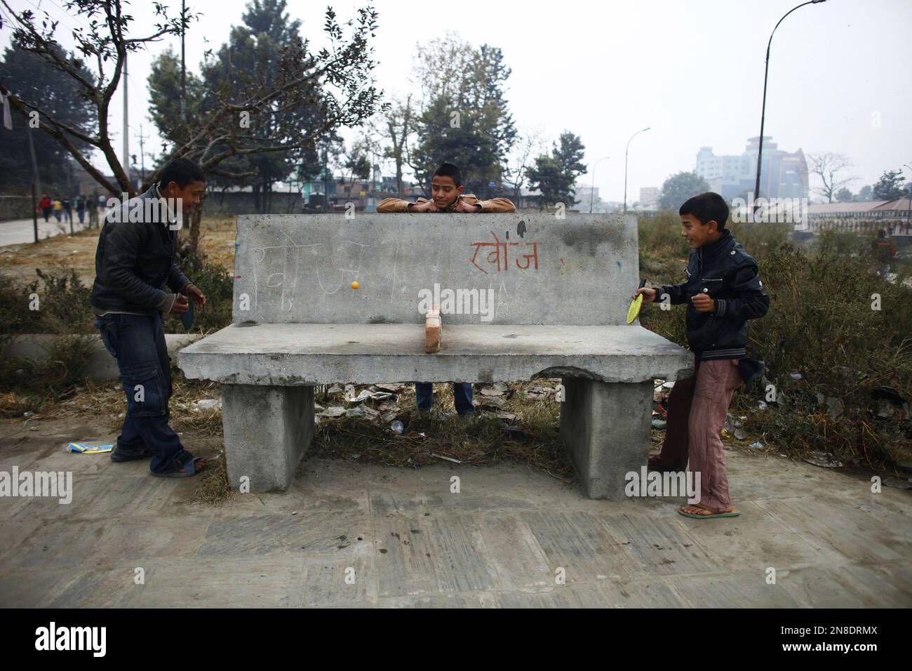 Nepalese children make use of a cement bench for a game of table tennis ...