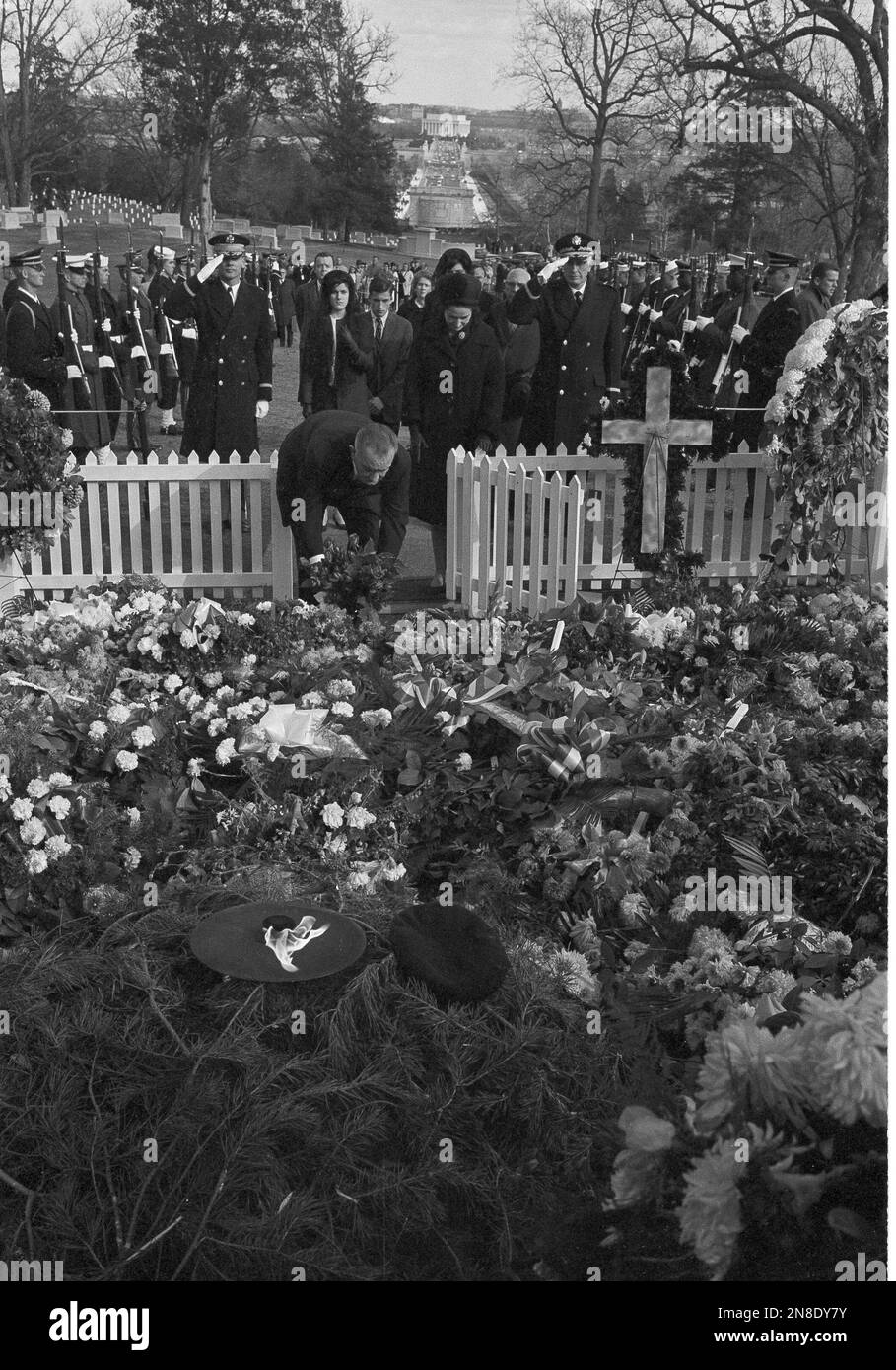 President Lyndon B. Johnson bends to place a bouquet of red roses on ...