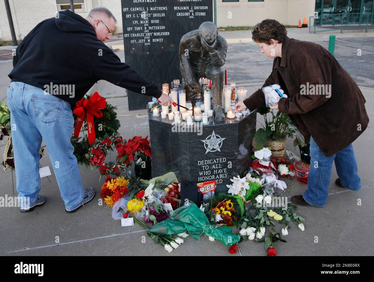 Topeka Police Lt. Jack Mackey, left, and Jennifer Walker light candles ...