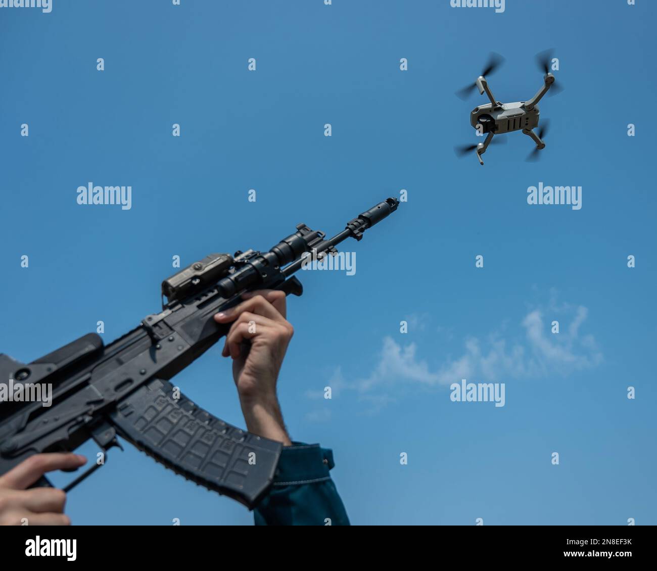 A man aims to shoot a rifle at a flying drone against a blue sky Stock ...