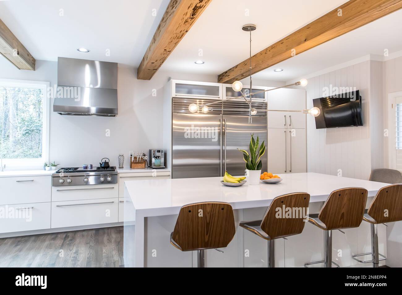 A large luxury modern kitchen with white walls and wood beams and a ...