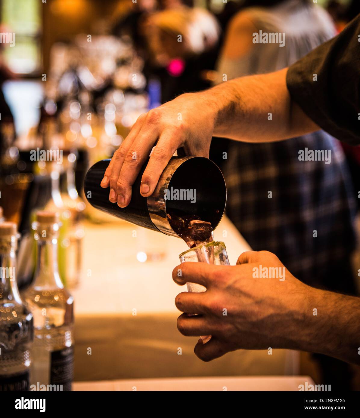 A male bartender hands showing the artistic talent of mixing drinks ...