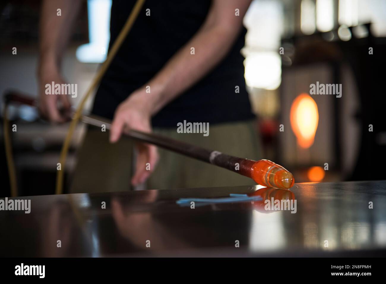 A glass blower holding glass mold with high temperature fire for ...