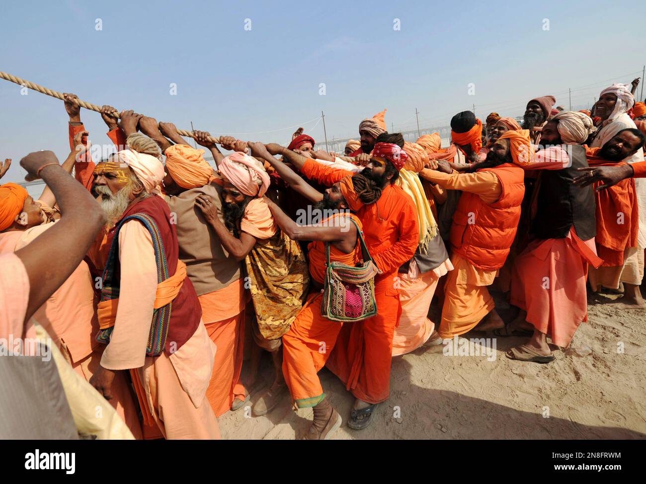 Sadhus, or Hindu holy men pull a rope to raise a religious flag at the ...