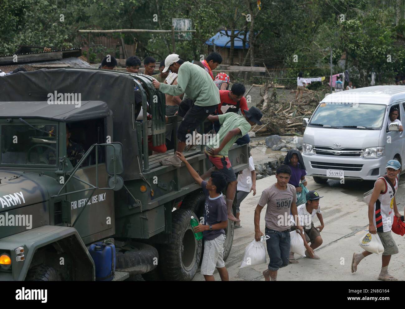 Residents jump off a military truck after receiving food supplies in ...