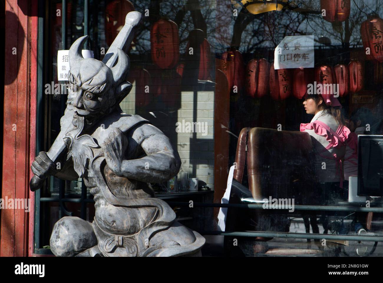 A waitress looks out near a statue depicting a ghost outside a ...