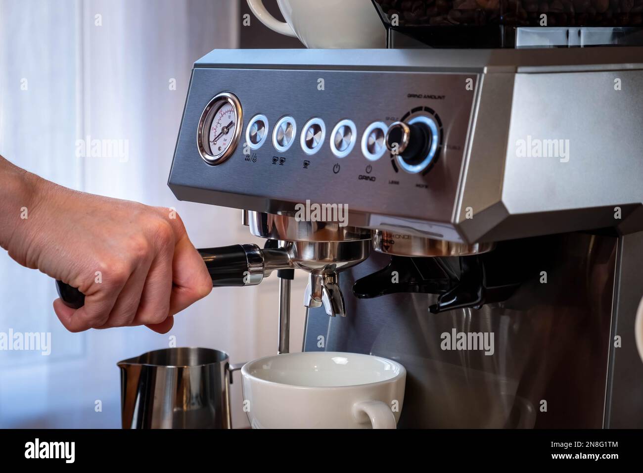 A barista locks the portafilter in place just before extracting an ...