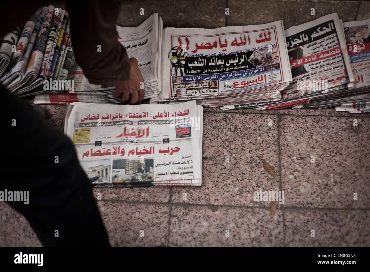 An Egyptian newspaperman arranges state-owned newspapers being sold on the street in Cairo ...