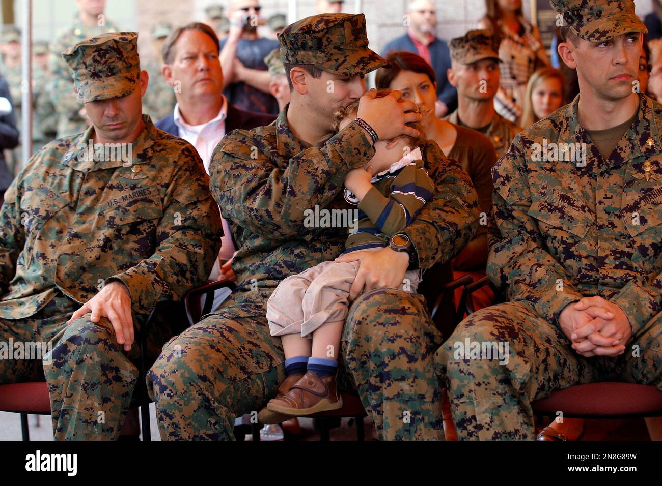 U.S. Navy Petty Officer 2nd Class Patrick Quill, center, kisses his 2 ...