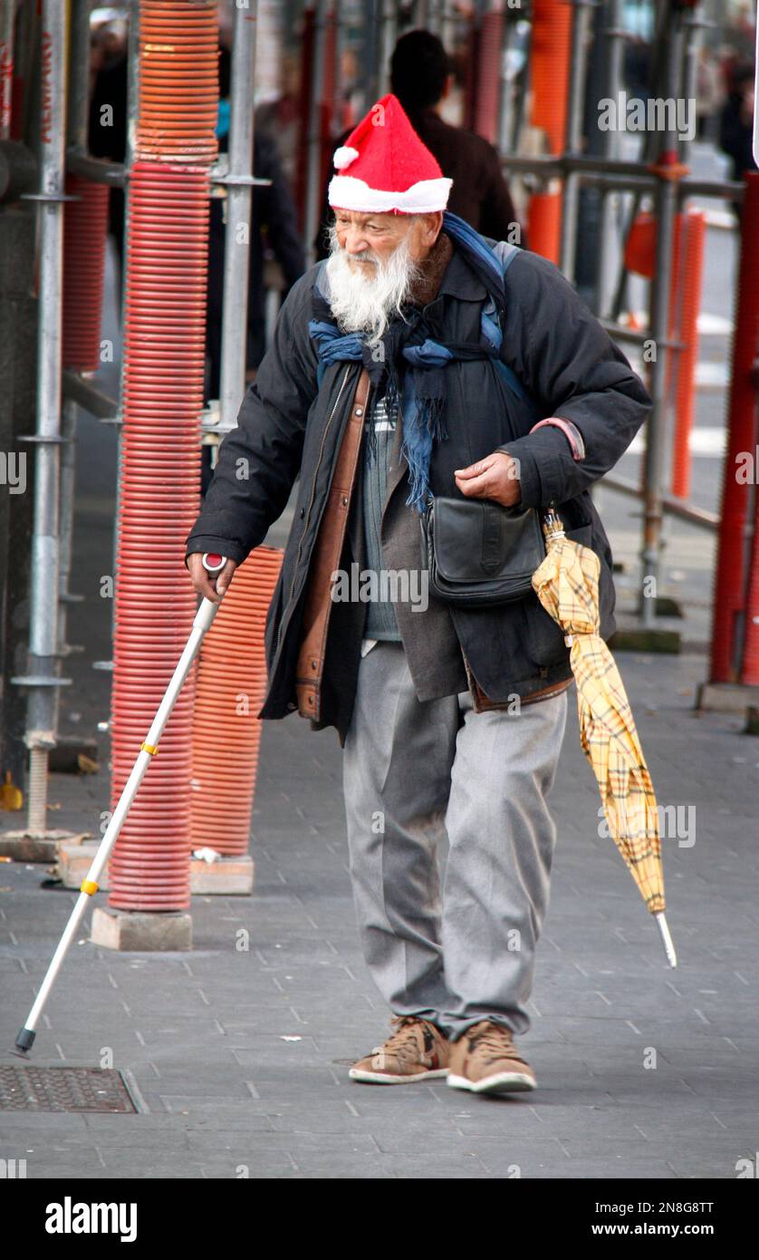 A homeless wearing a Santa Claus hat, walks in the street of Nice ...