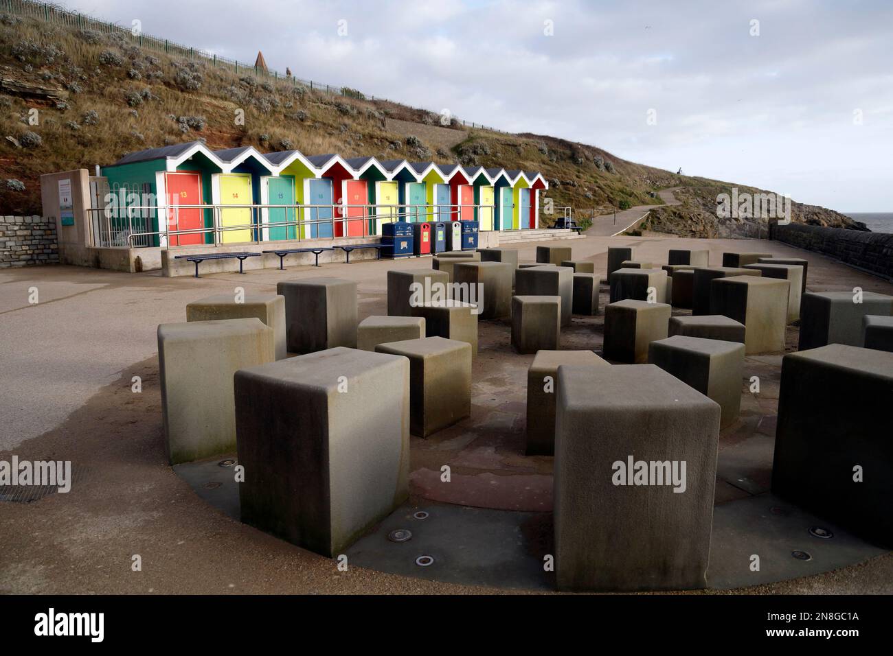 Beach huts and art installation - called 'Ammonite' - stone blocks ...