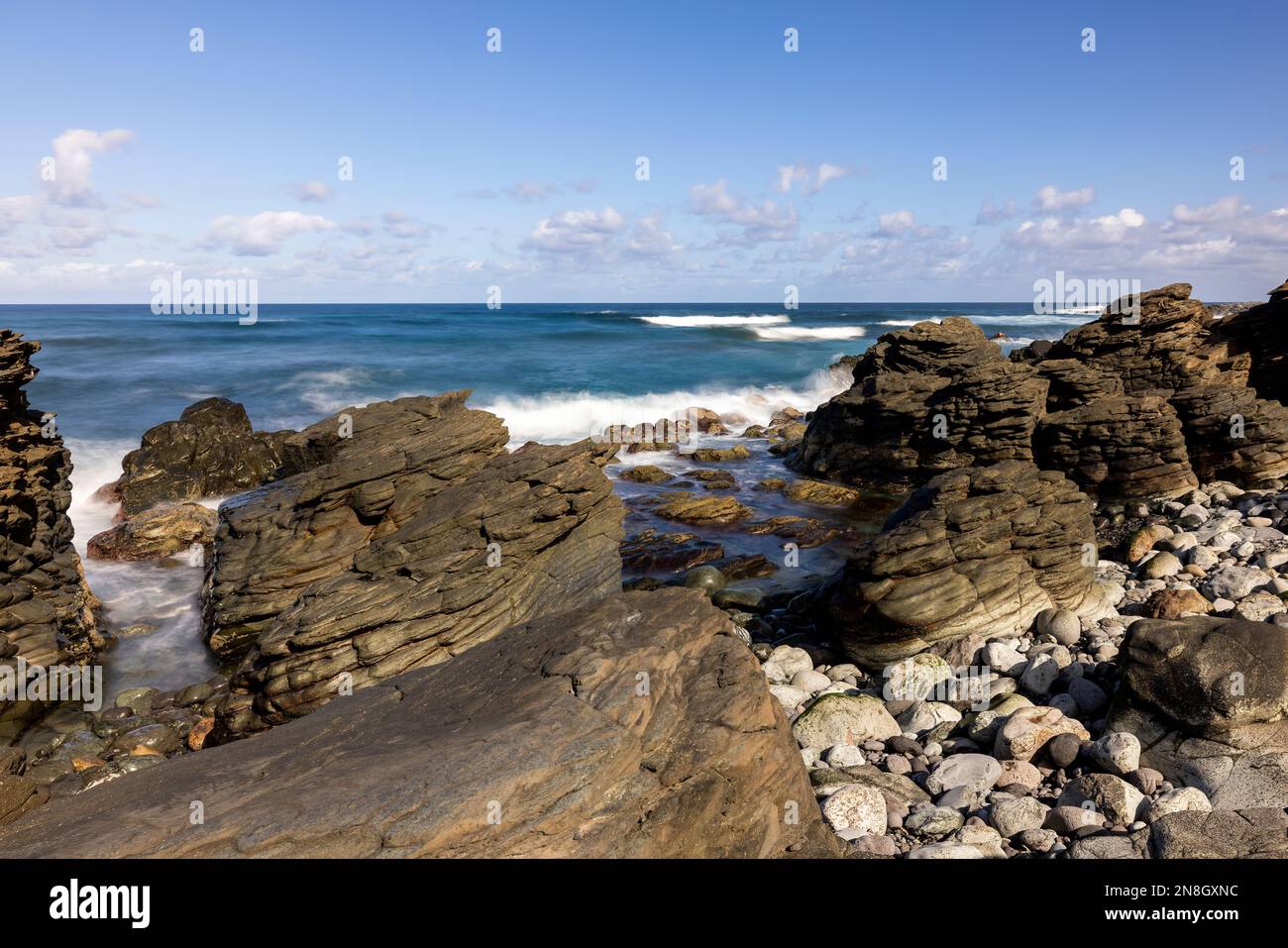 Nature's Fury: The ocean's waves hitting rocks on the shore at daylight ...