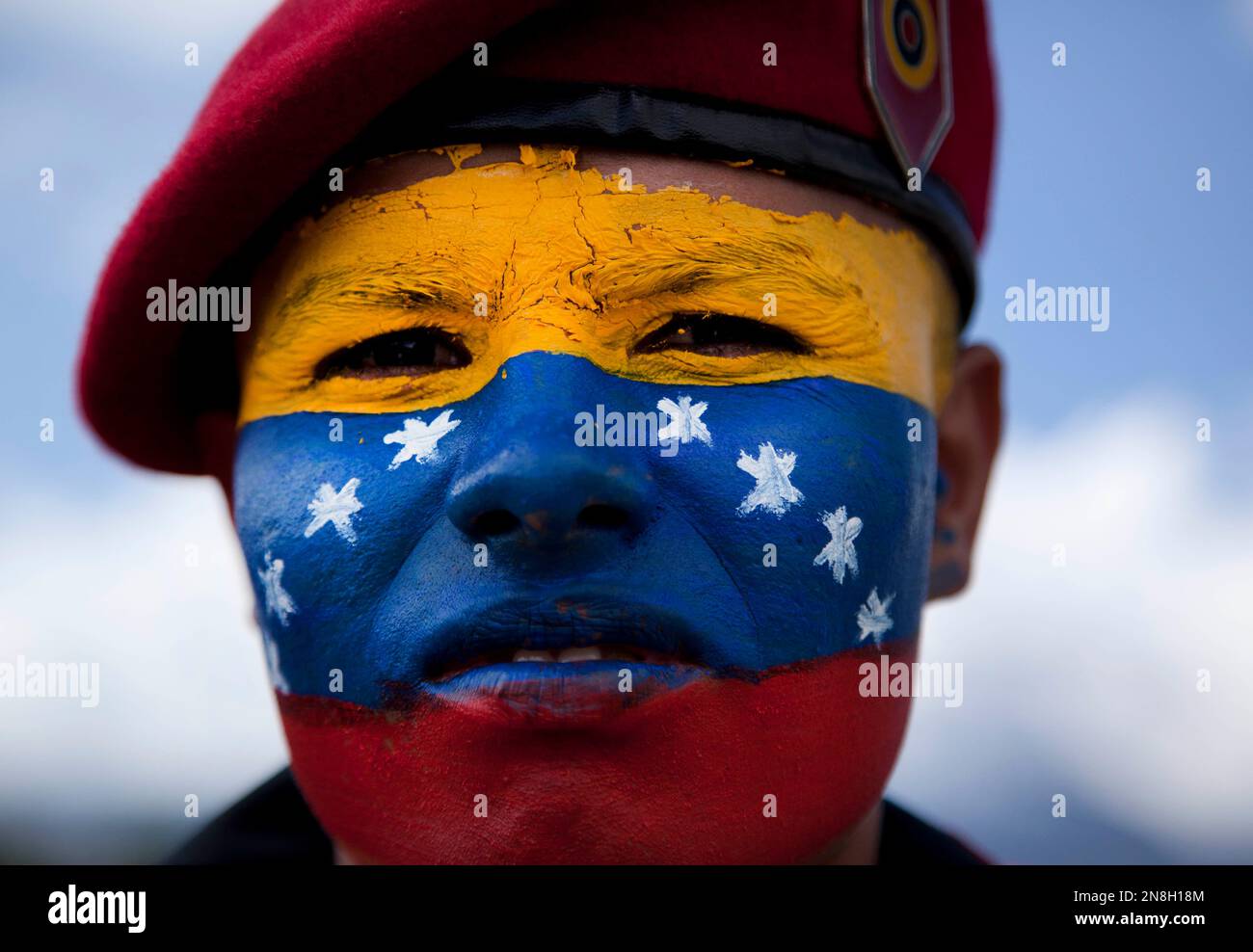 A soldier with his face painted with the colors of the Venezuelan flag ...