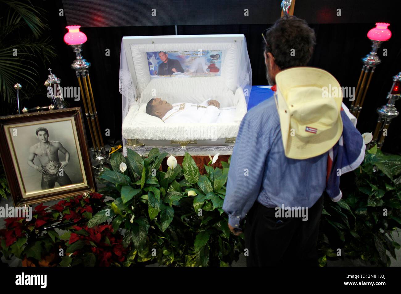 A man stands in front of the open casket of former boxing champion ...
