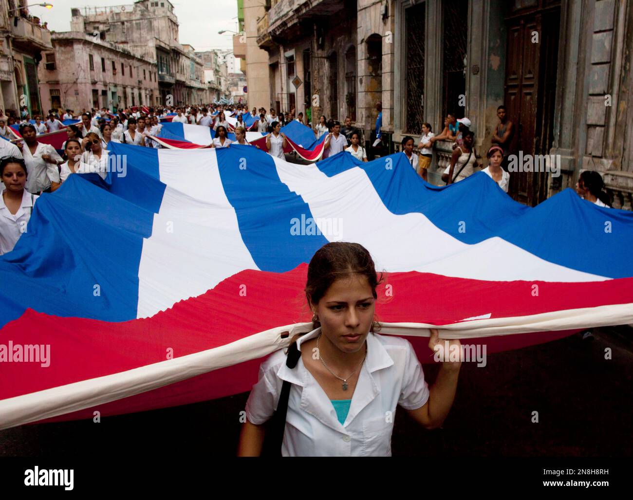Students carry Cuba's national flag during a march marking the 141th ...
