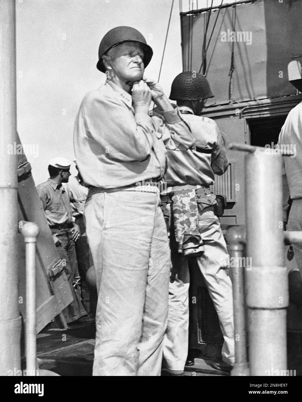 Admiral Chester Nimitz fastens the chin strap on his helmet while ...