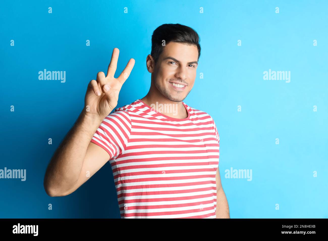 Man showing number two with his hand on light blue background Stock ...