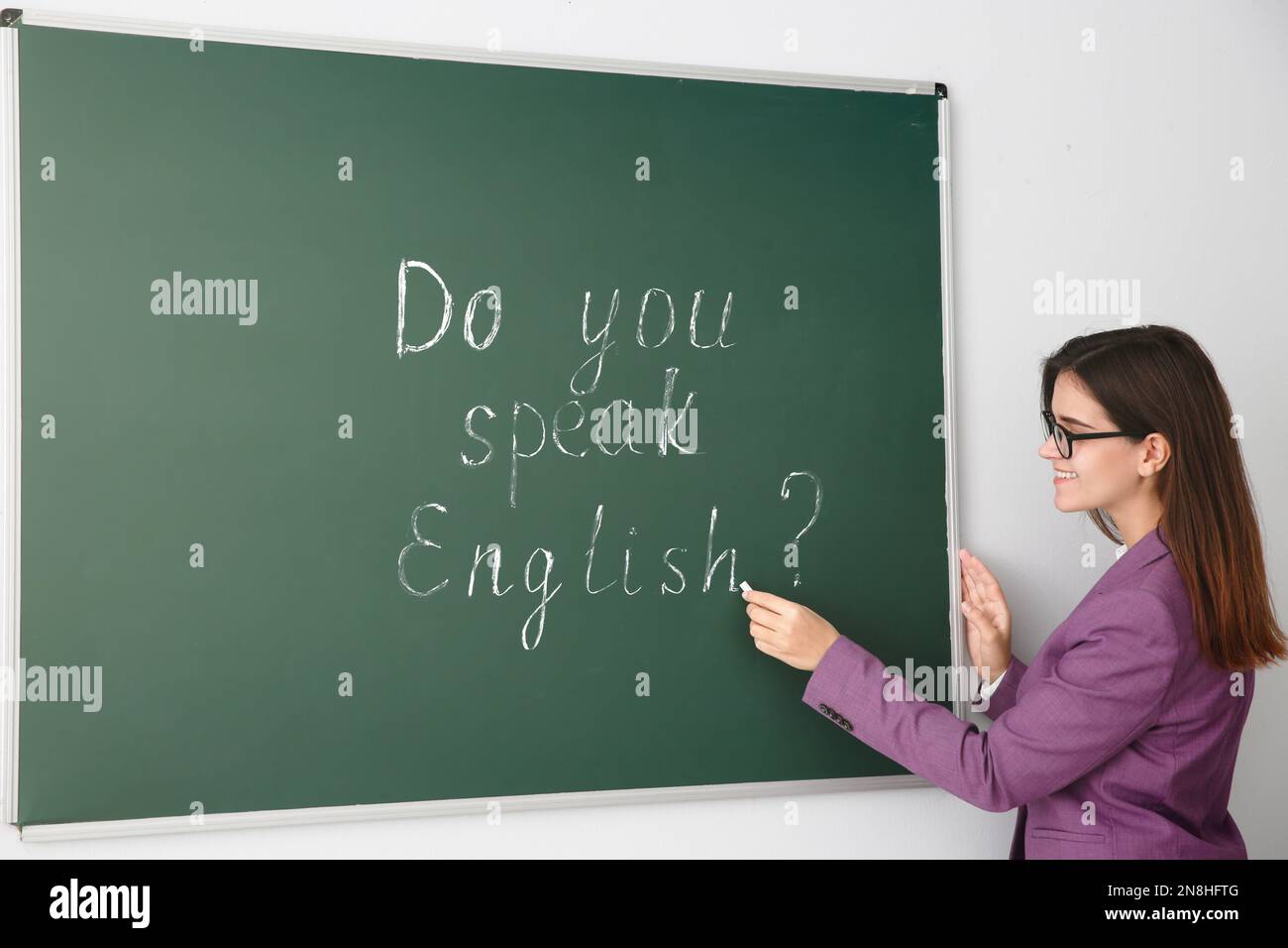 Teacher near green chalkboard with words Do You Speak English Stock ...