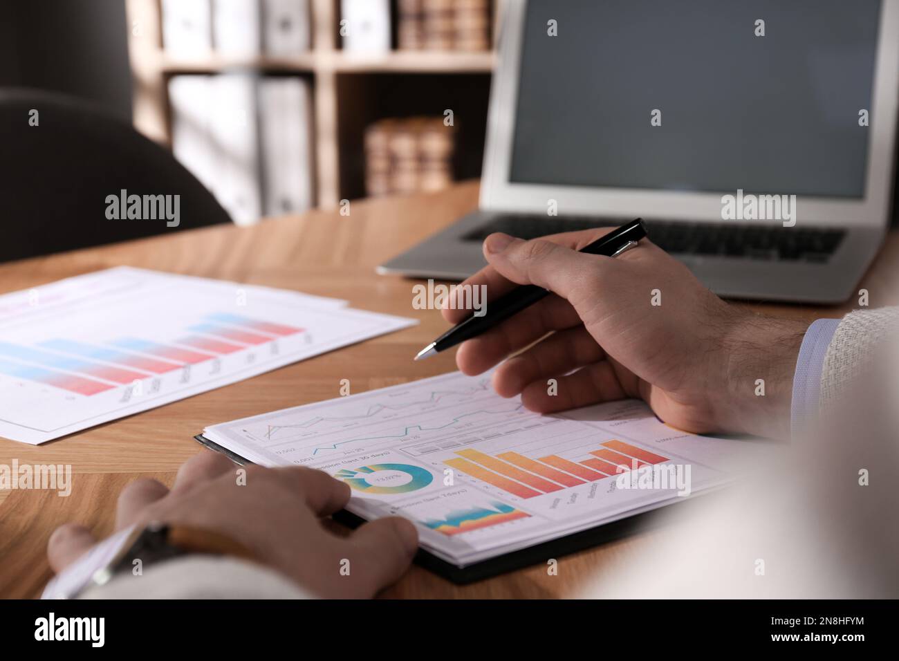 Businessman working with charts and graphs at table in office, closeup ...