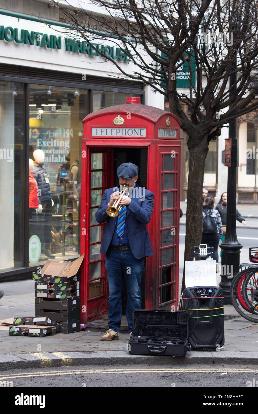 Busker with trumpet standing in a dirty red London Phone box Stock ...