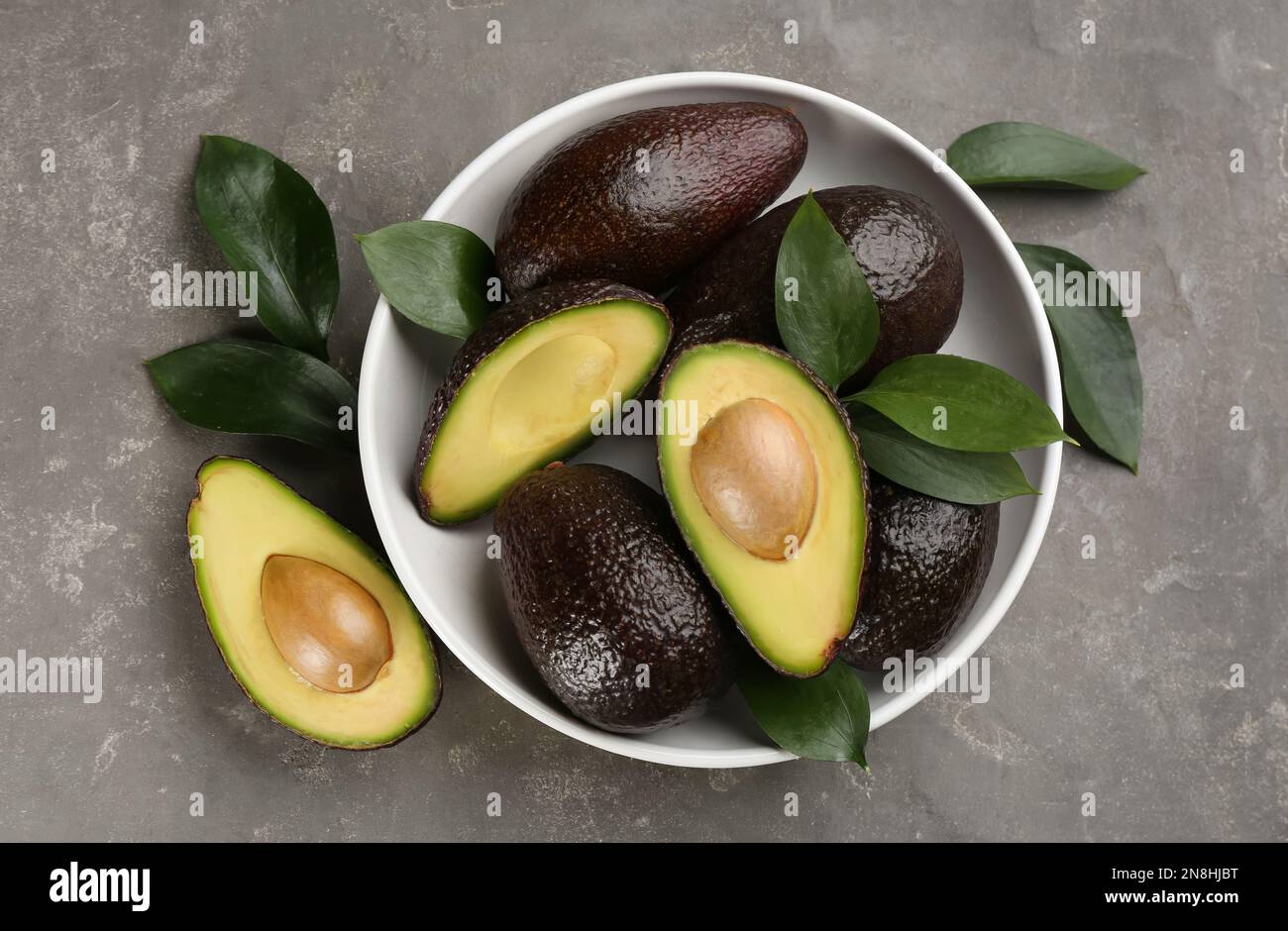 Whole and cut avocados on grey table, flat lay Stock Photo - Alamy