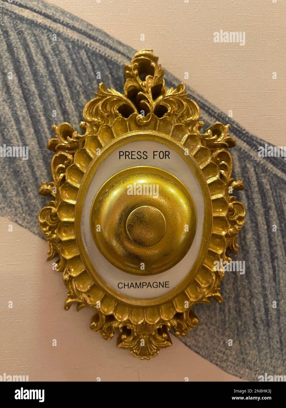 A vertical shot of a golden "press for champagne' button with retro ...