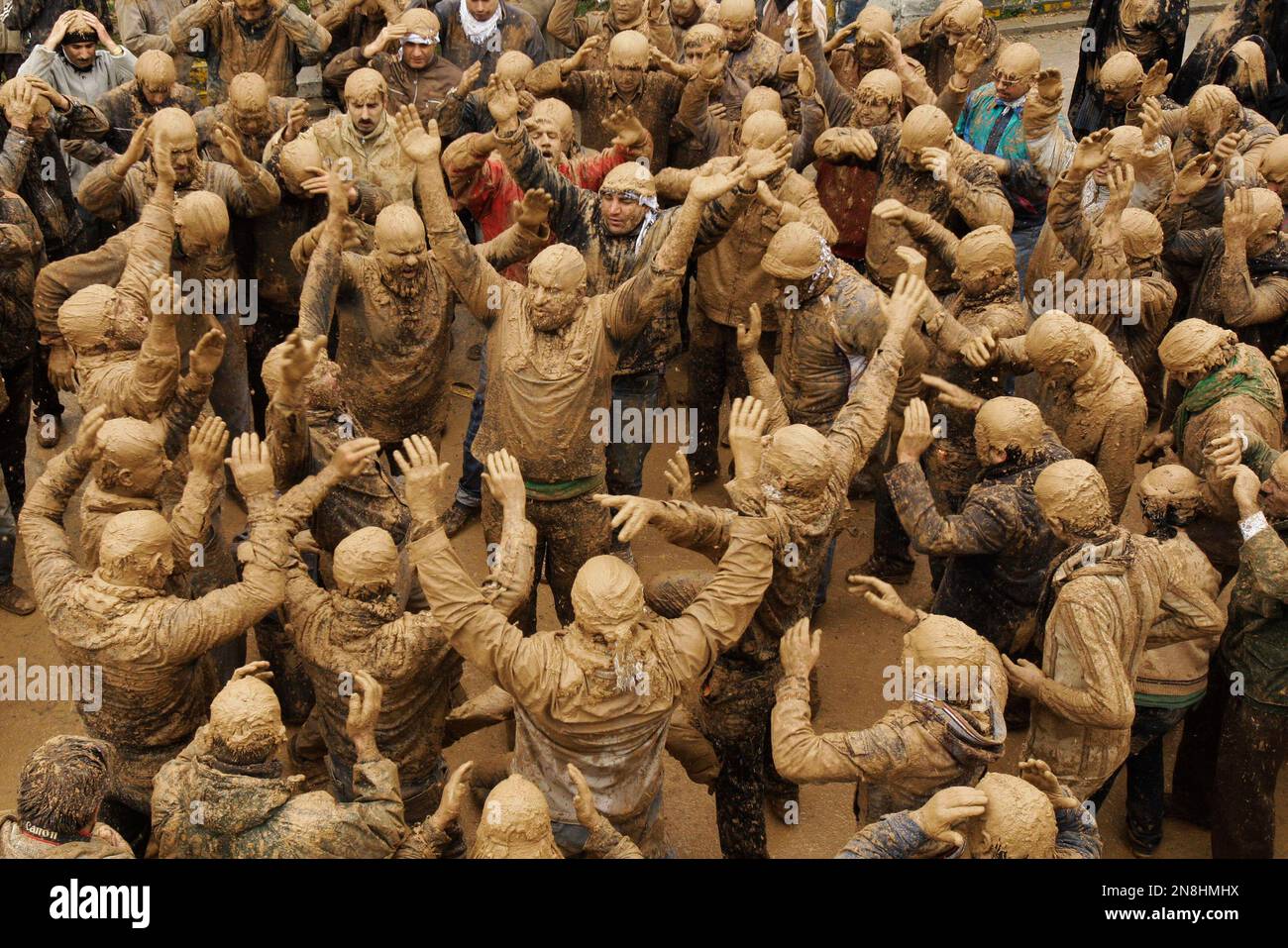Iranian mourners chant slogans, as they cover themselves with mud ...