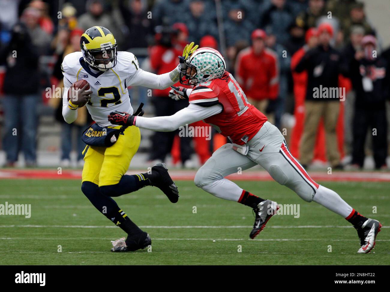 Michigan quarterback Devin Gardner (12) wards off Ohio State linebacker ...