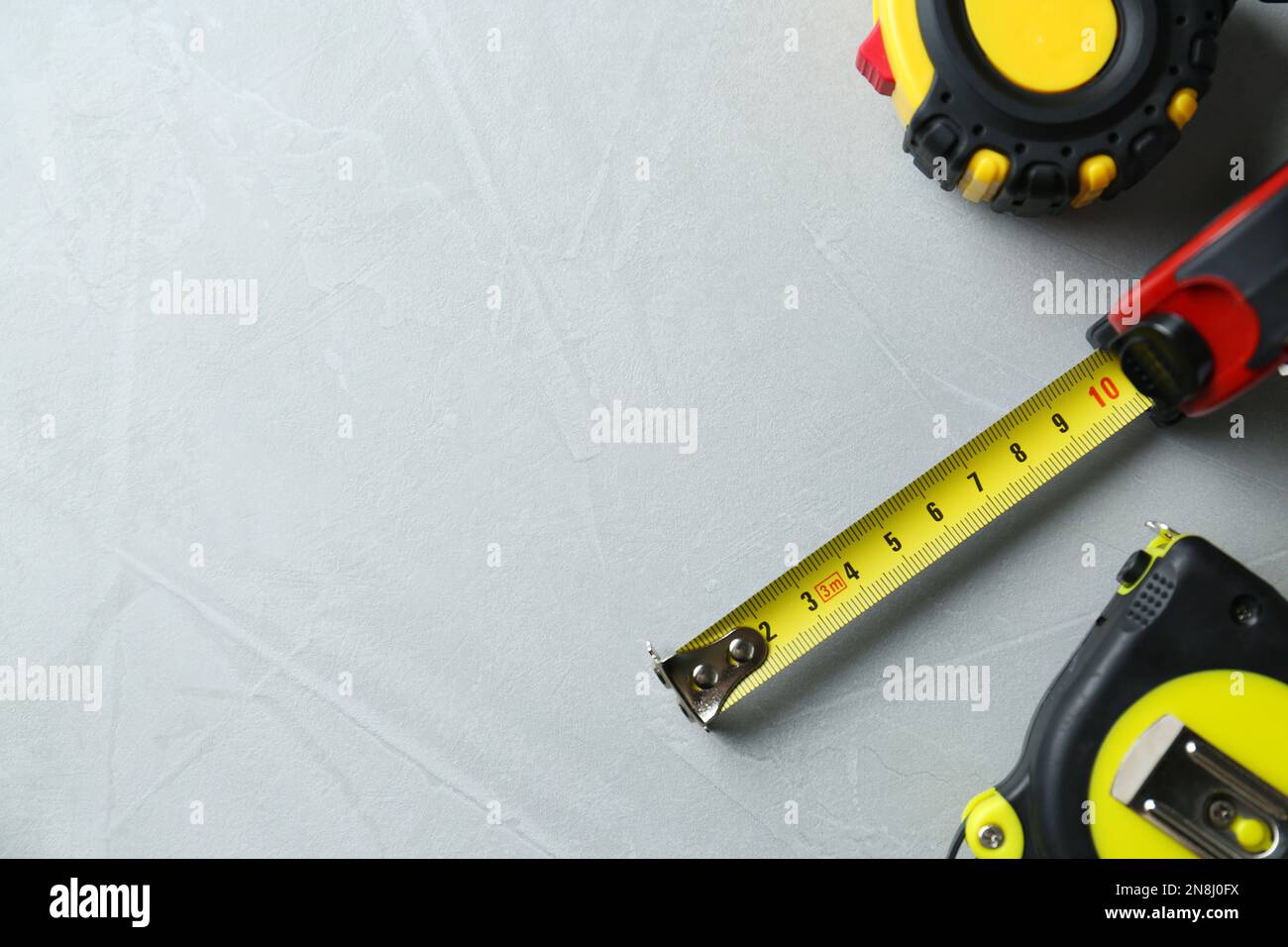 Tapes measure on light grey background, flat lay. Space for text Stock ...
