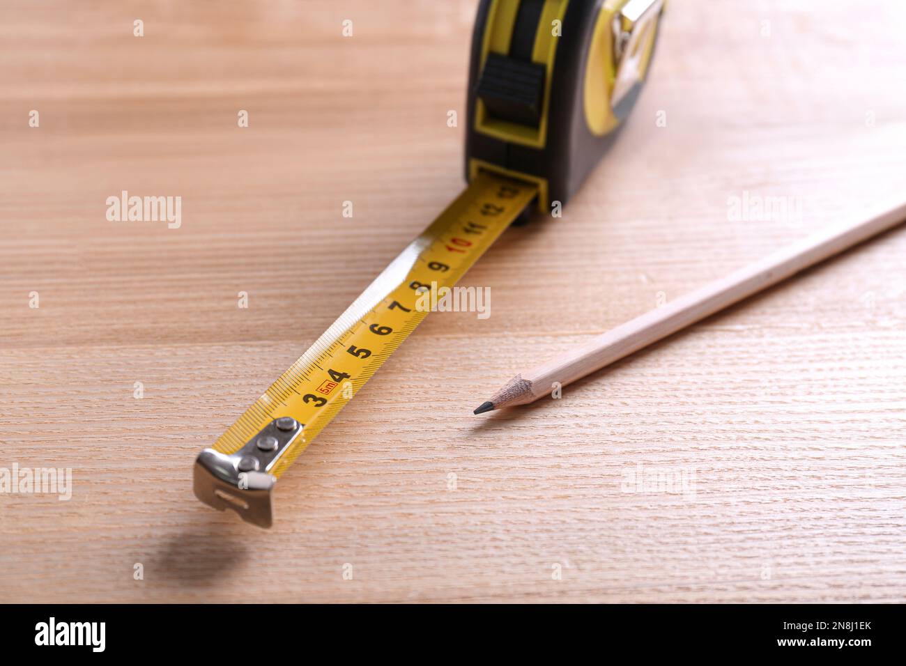 Self retracting metal measuring tape and pencil on wooden table ...