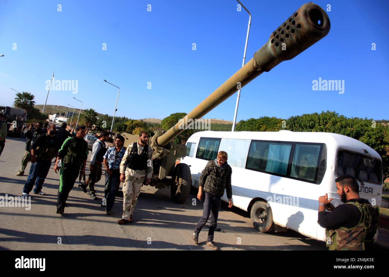 Syrian fighters walk past an artillery canon they took after storming a ...