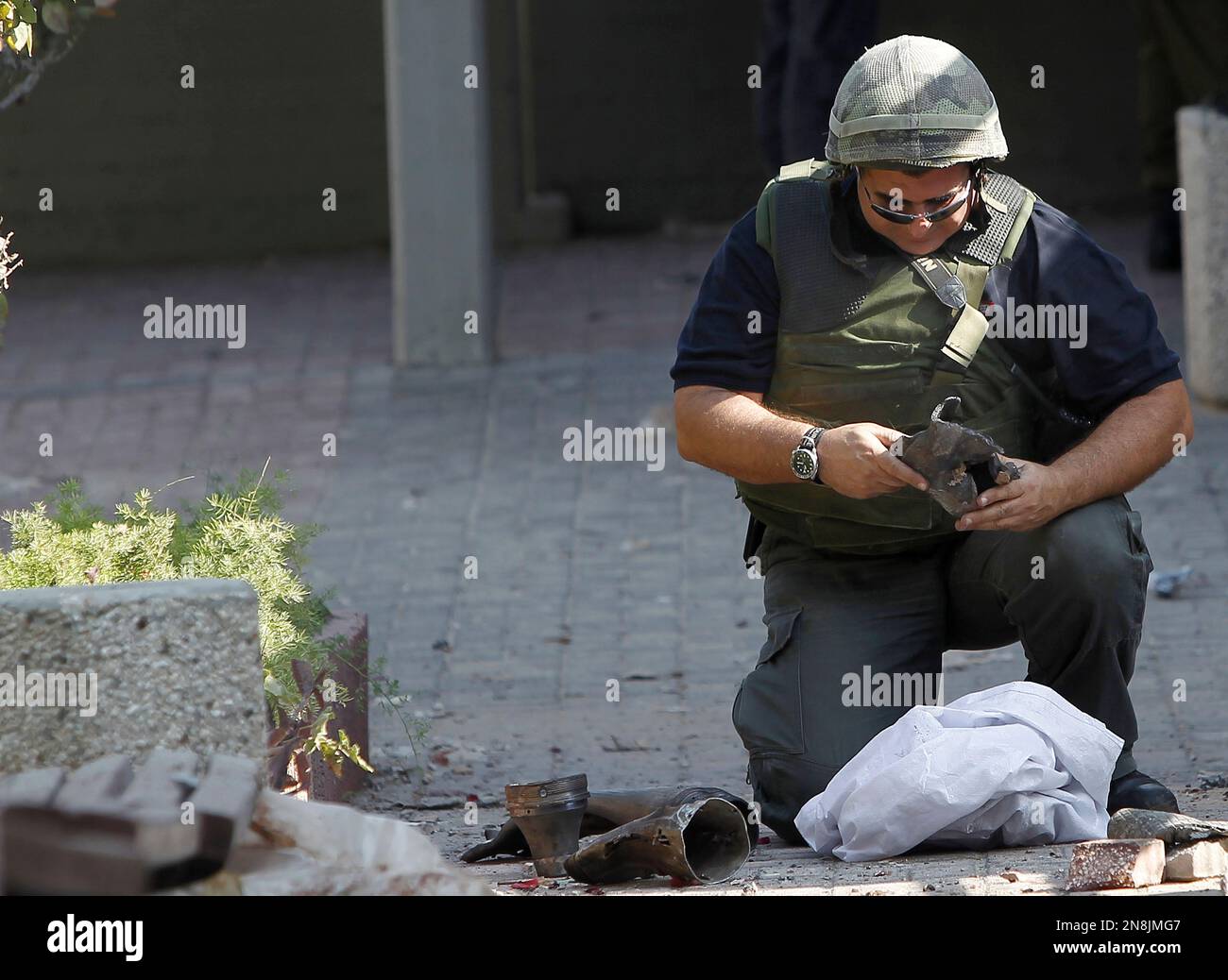 An Israeli police sapper collects the remains of a ordnance fired by ...