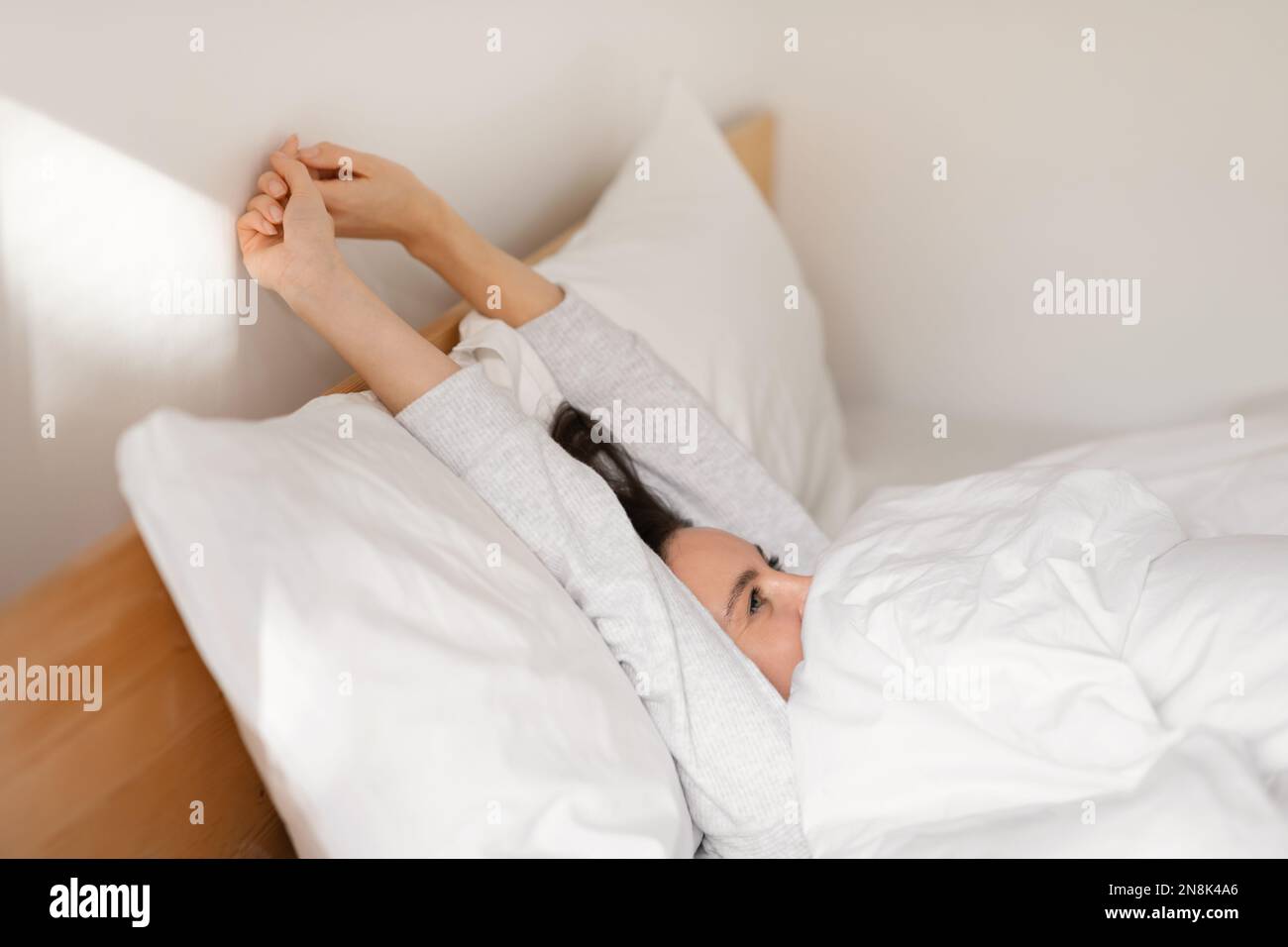 Smiling caucasian millennial lady sleeping on comfortable bed, wake up ...