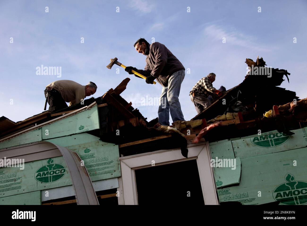 John Toto, center, works with friends to demolish his house in the ...