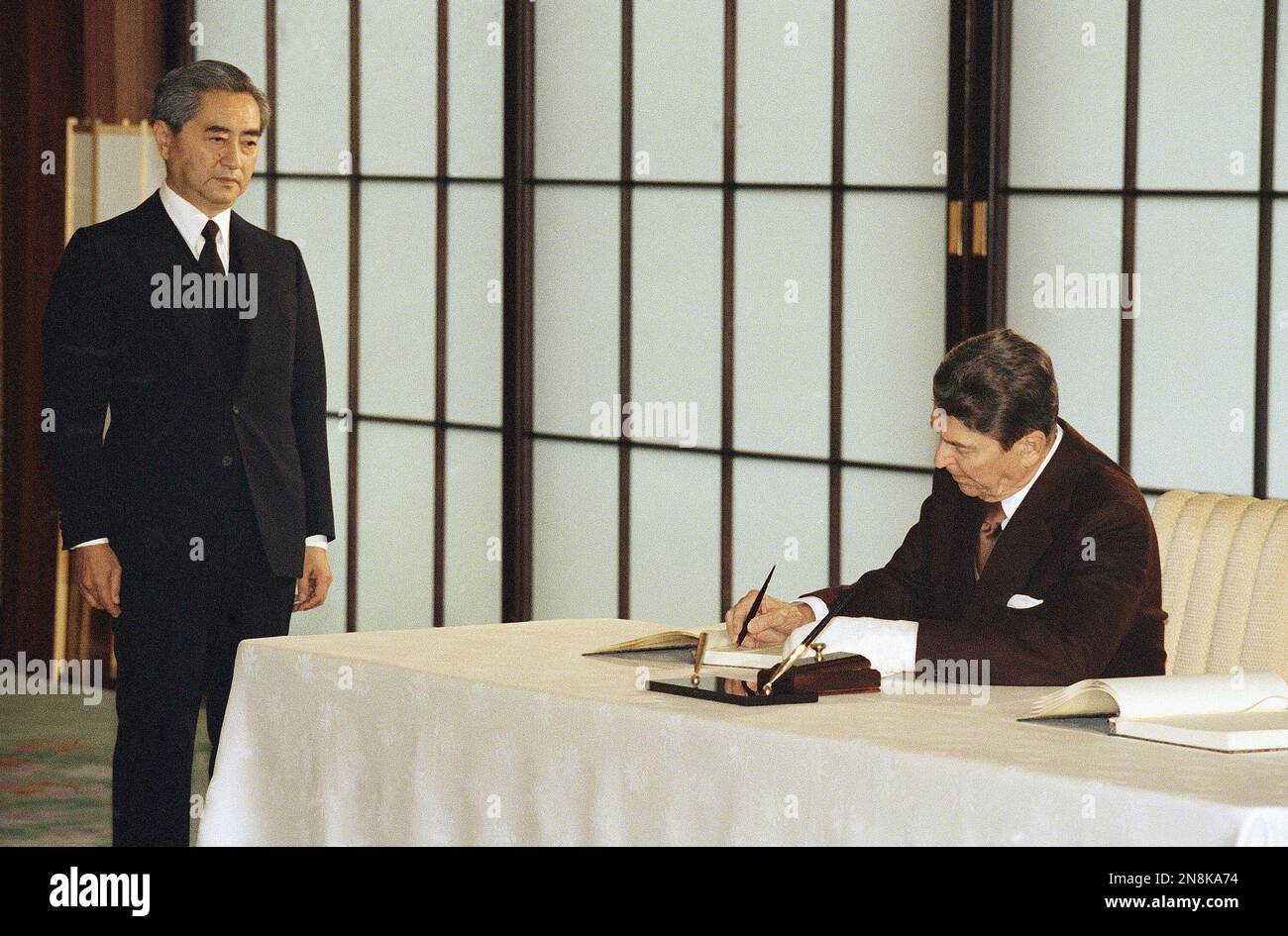 President Ronald Reagan signs a book of condolences for the late Japanese Emperor Hirohito as ...