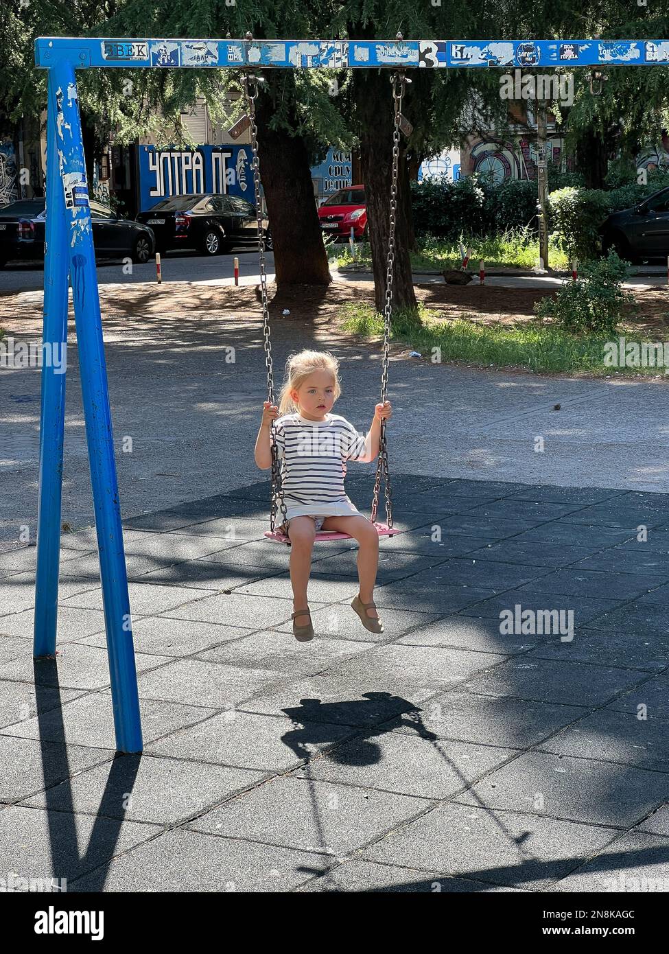Little girl sits on a chain swing on the playground Stock Photo - Alamy