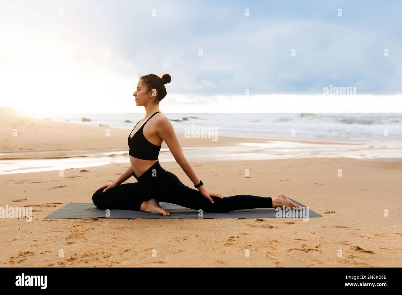 Outdoor sports. Fit young lady doing stretching exercises outside ...