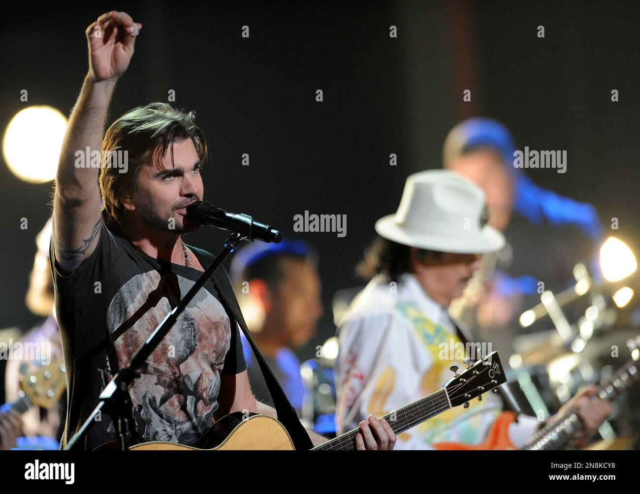 Juanes, left, and Santana, in background, perform "Fijate Bien" at the ...