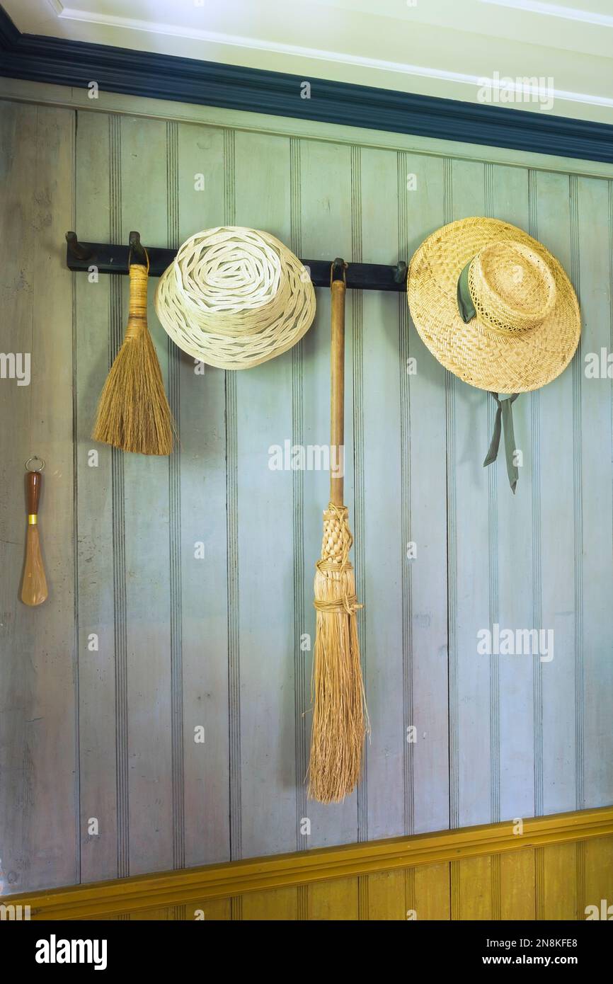 Vintage weaved straw hats and broomsticks hangimg on light green ...
