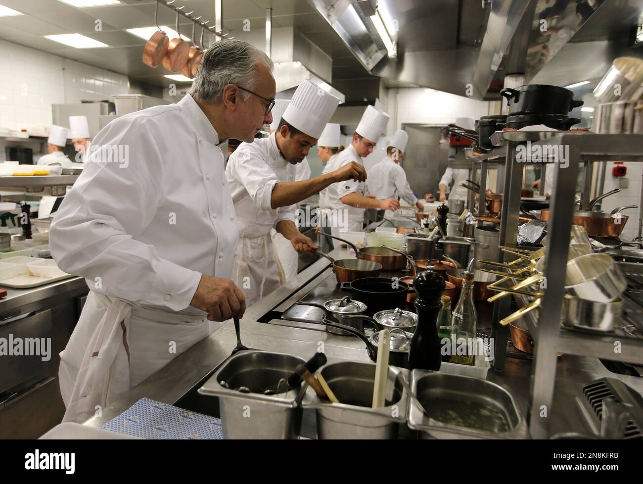 French chef Alain Ducasse looks at his chefs in the kitchen of his ...