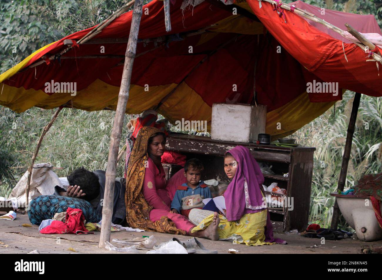 A Pakistani family sit in their make-shift tent in the slums of Lahore ...