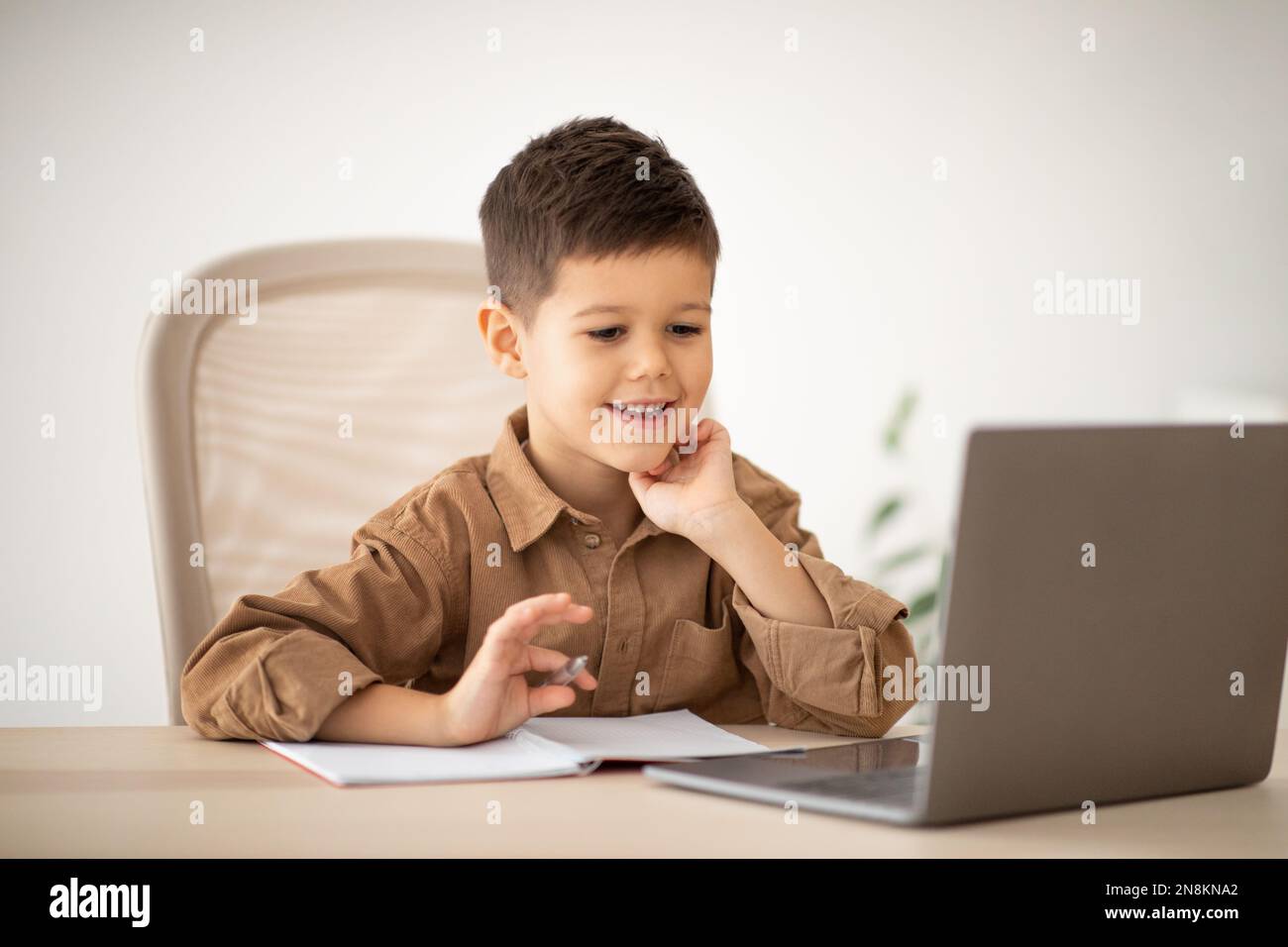 Elementary education remotely. Smiling caucasian little child sit at ...