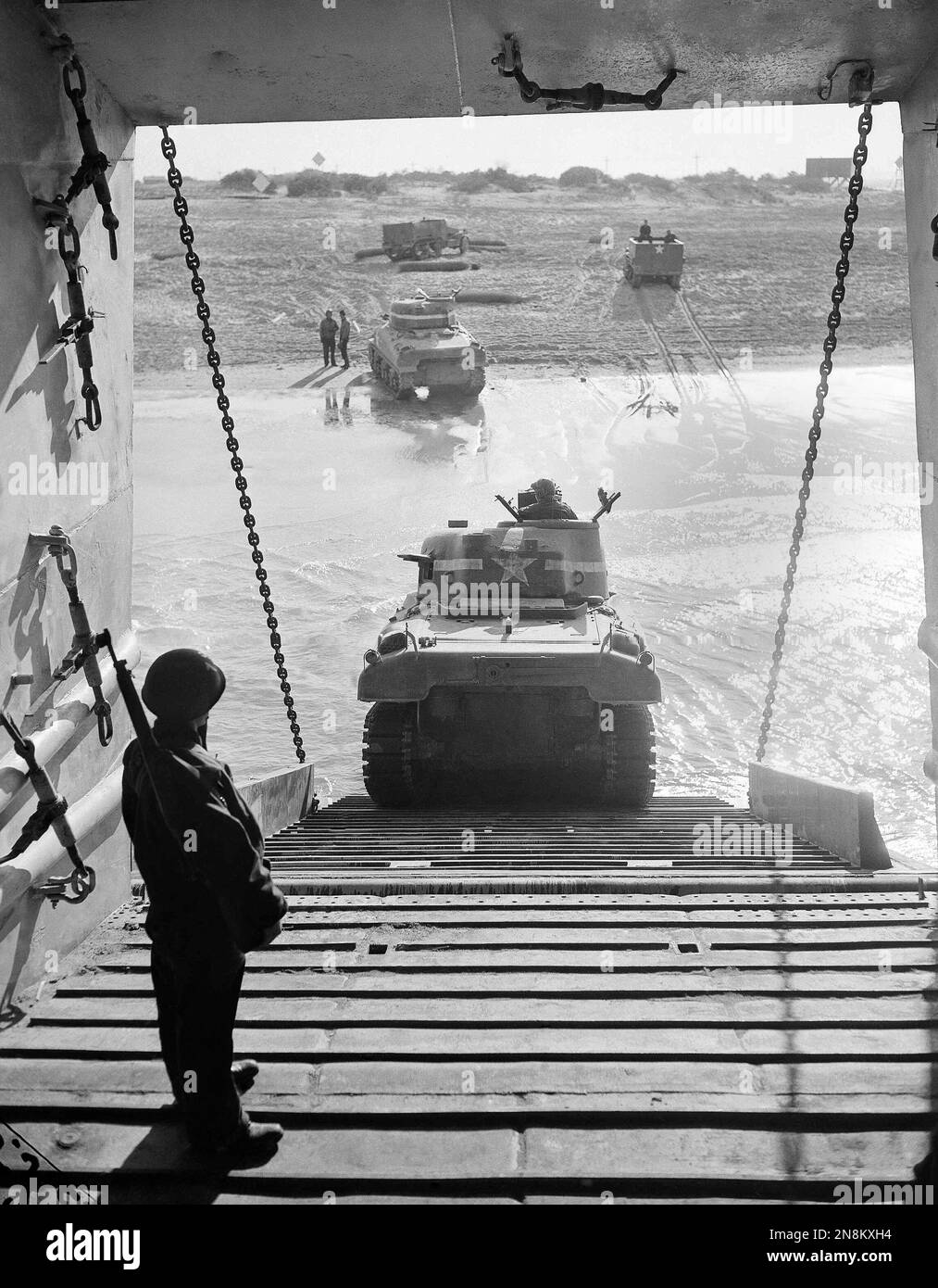Tanks trundle down the ramp and ashore from an LST (Landing Ship Tanks ...