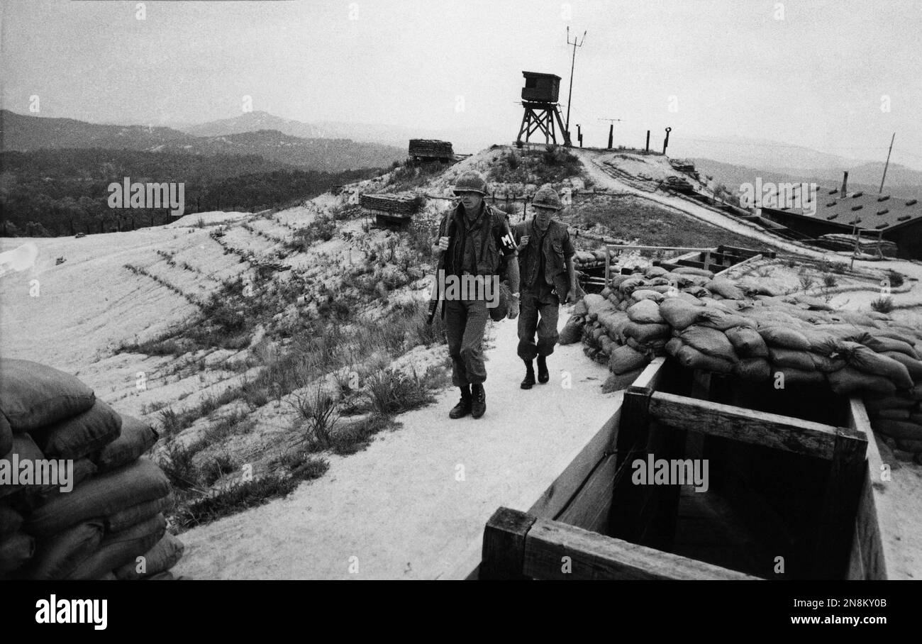Two American GIs in battle outfit patrol along a ridge between ...