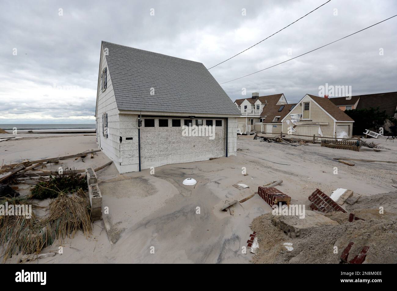 Sand and debris surround houses that were damaged by surge from ...