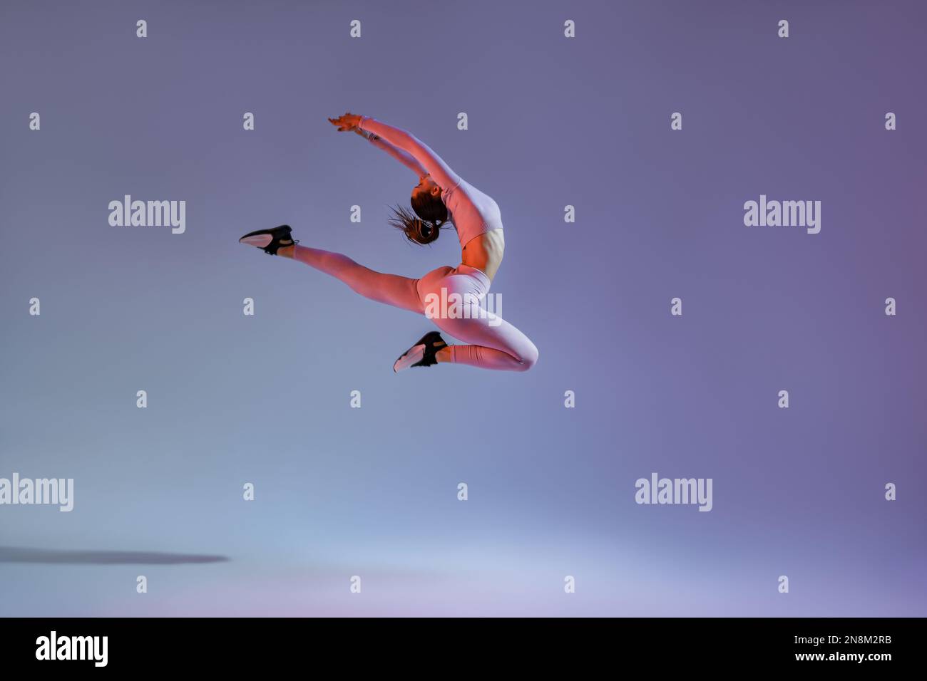 Sporty girl jumping doing split leap in air with joyful expression ...