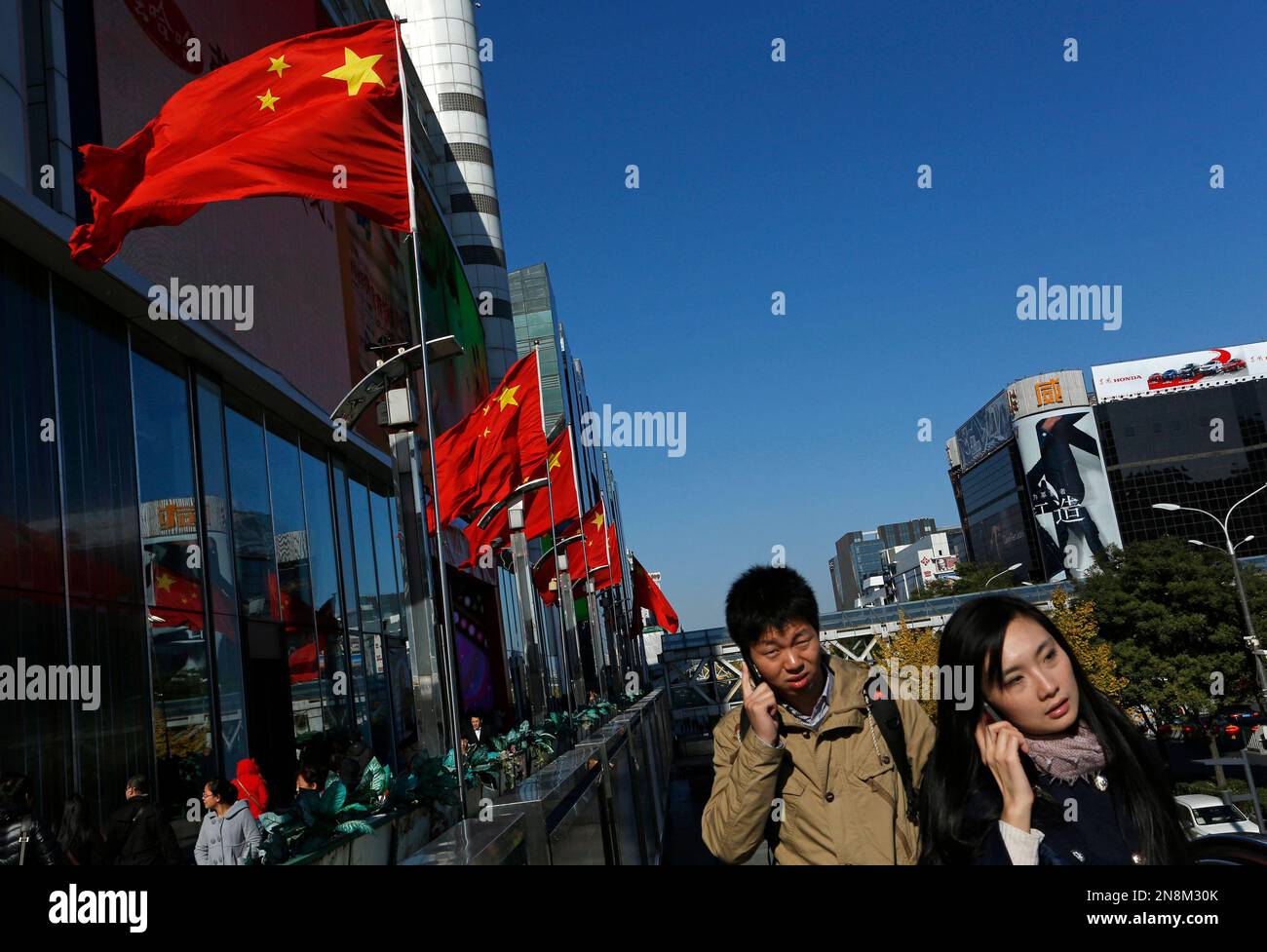 Chinese people talk on mobile phones outside a shopping mall in Beijing ...