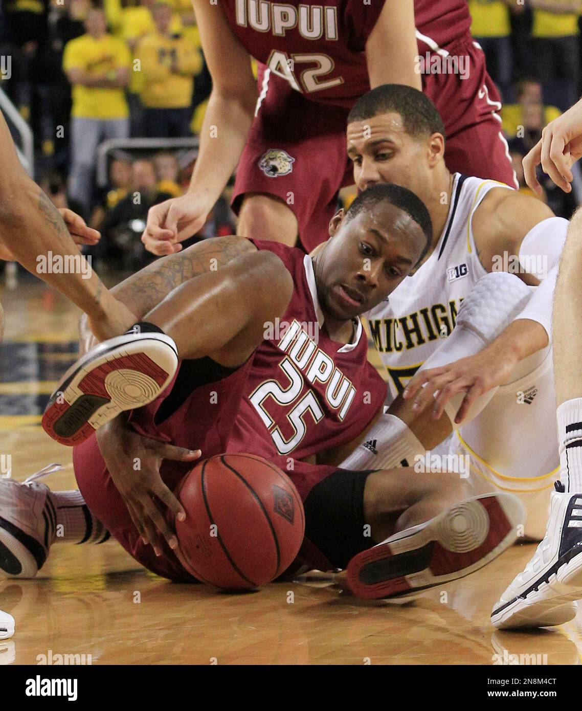 IUPUI guard John Hart (25) tries to control the ball as Michigan guard ...